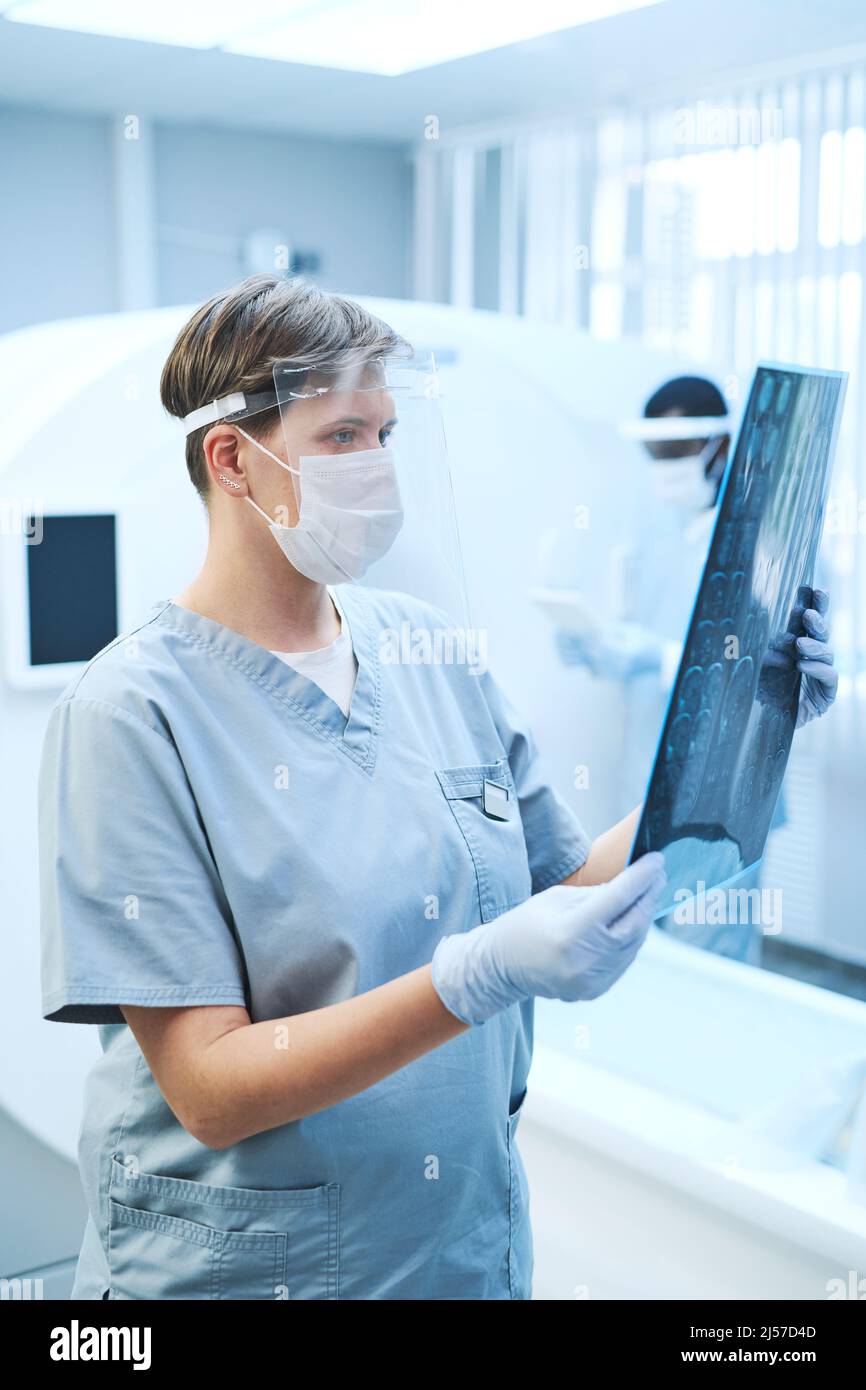 Concentrated Caucasian radiographer in mask and gloves standing against ...