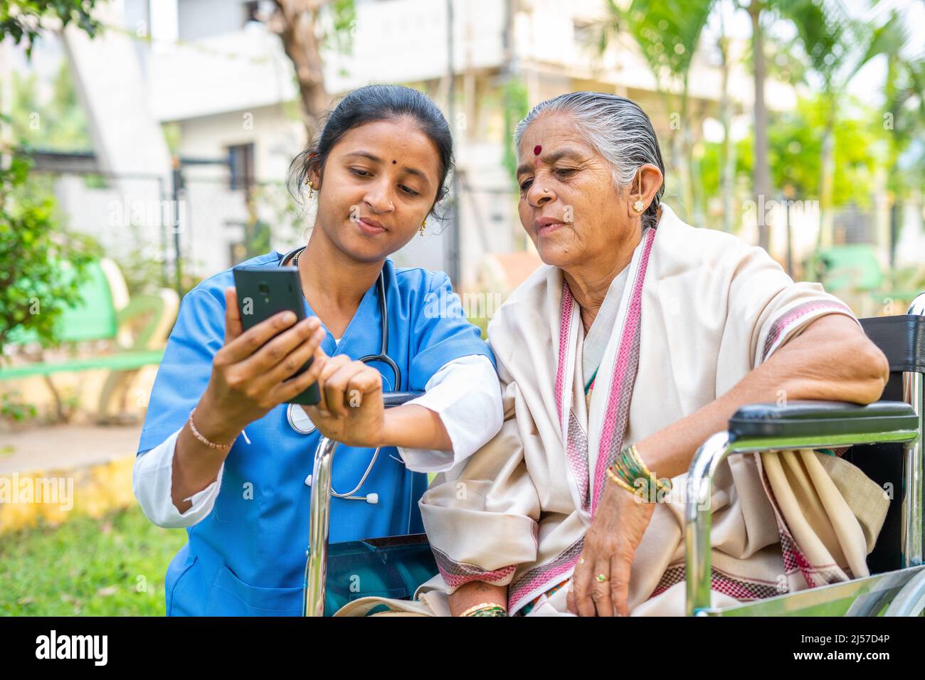 Nurse showing healthcare tips on mobile phone to seniorn patient while ...