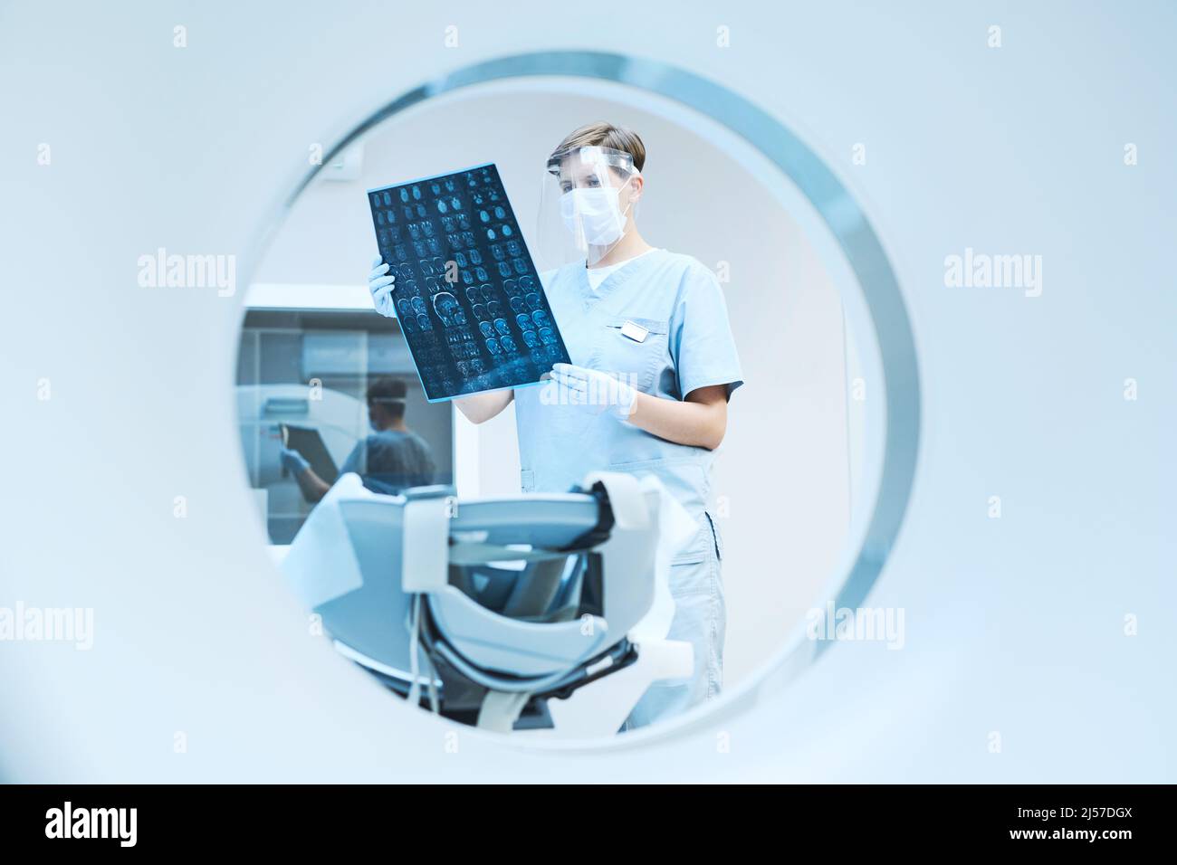 MRI bore view of radiologist in safety face shield viewing x-ray image ...