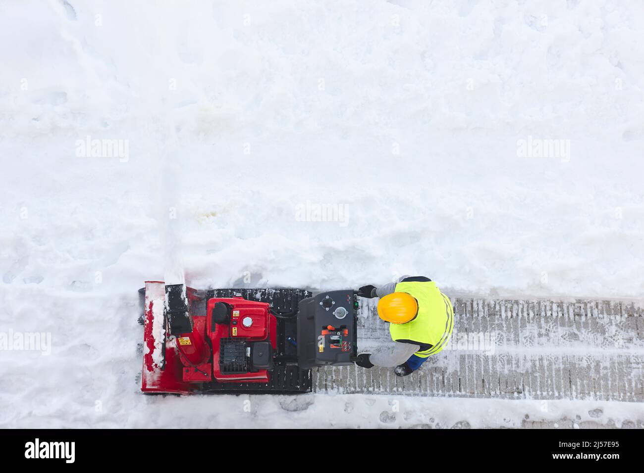 Worker cleaning snow on the sidewalk with a snowblower. Maintenance ...