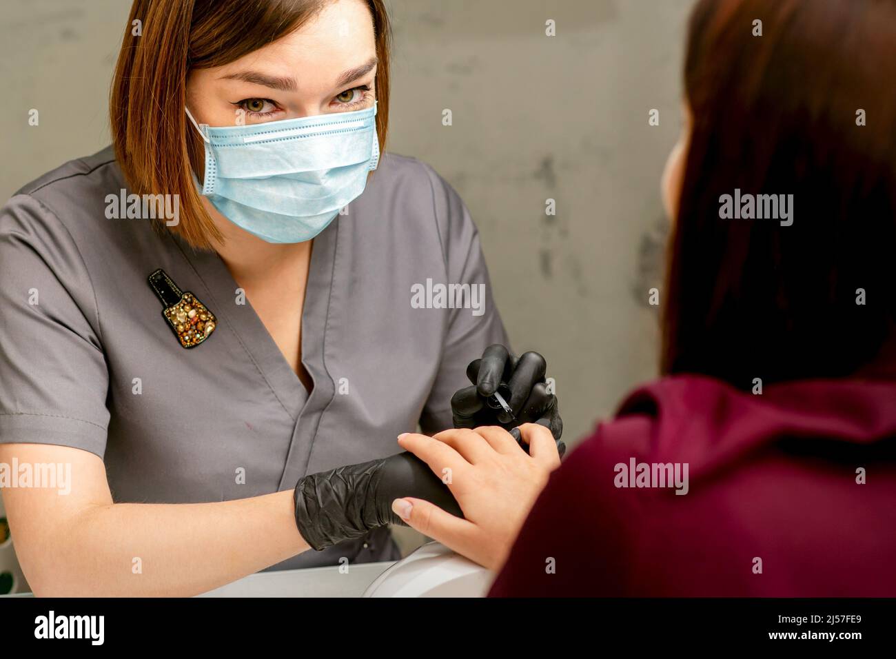 Portrait of young caucasian manicure master wearing protective mask ...