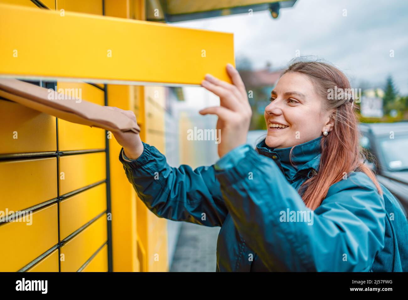 Caucasian woman send or receive parcel with self service post terminal ...