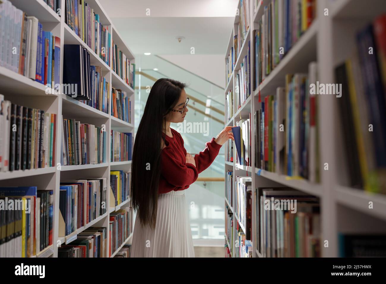 Girl asian student choose novel for project pick book from bookshelf in ...