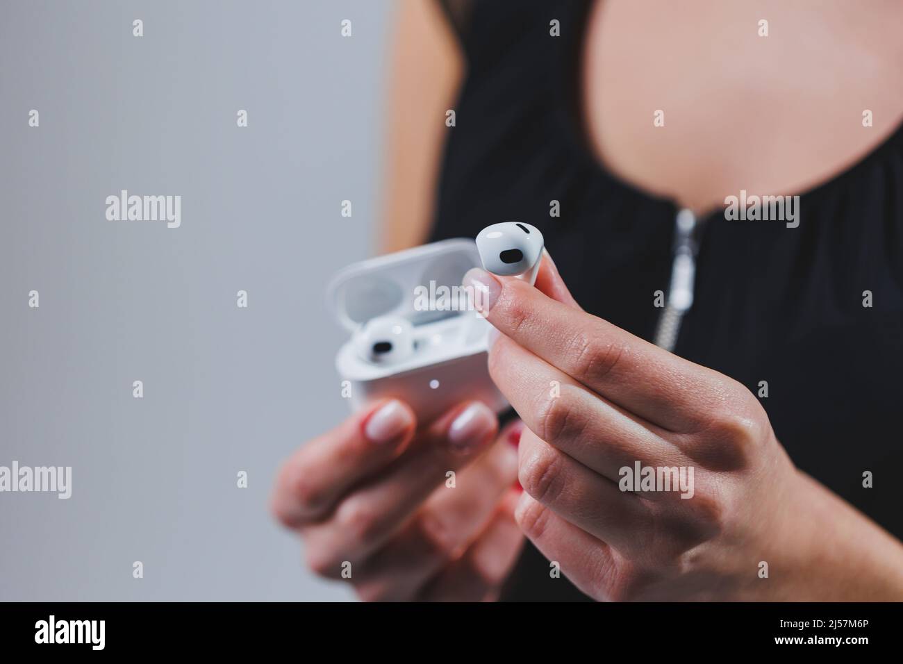 White wireless headphones in a woman's hand, close-up. Headset with ...