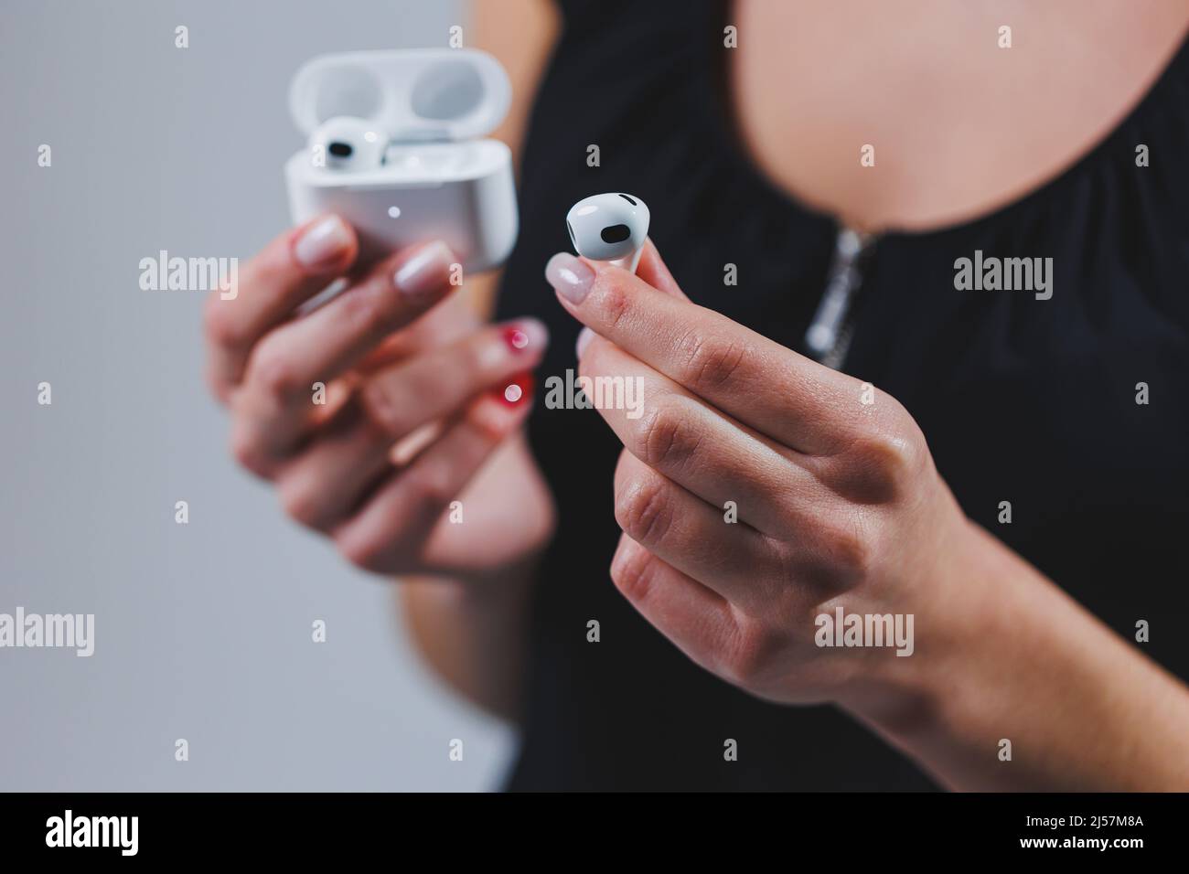 White wireless headphones in a woman's hand, close-up. Headset with ...