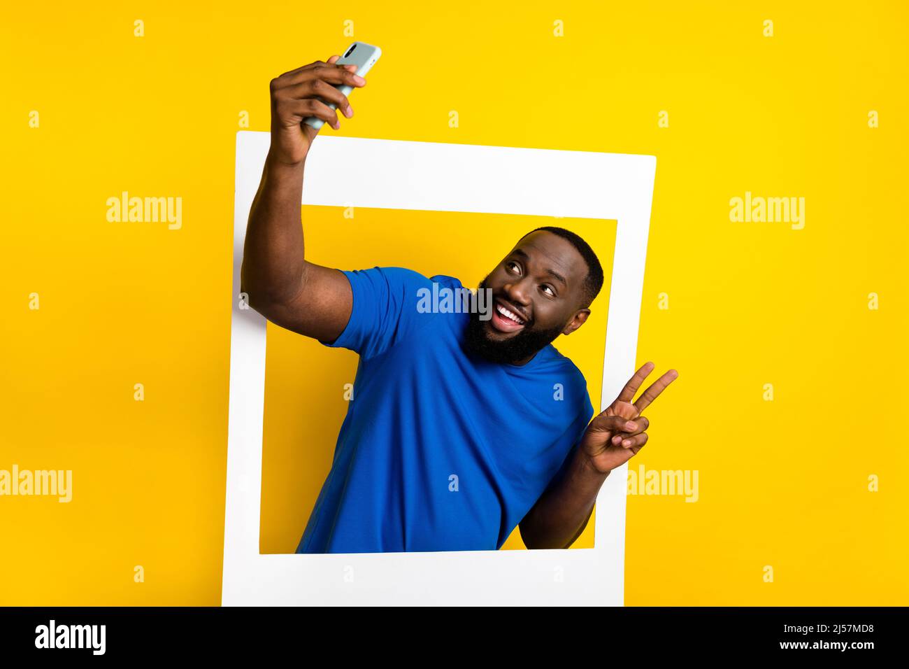 Portrait of handsome trendy cheerful guy coming out of photo frame ...