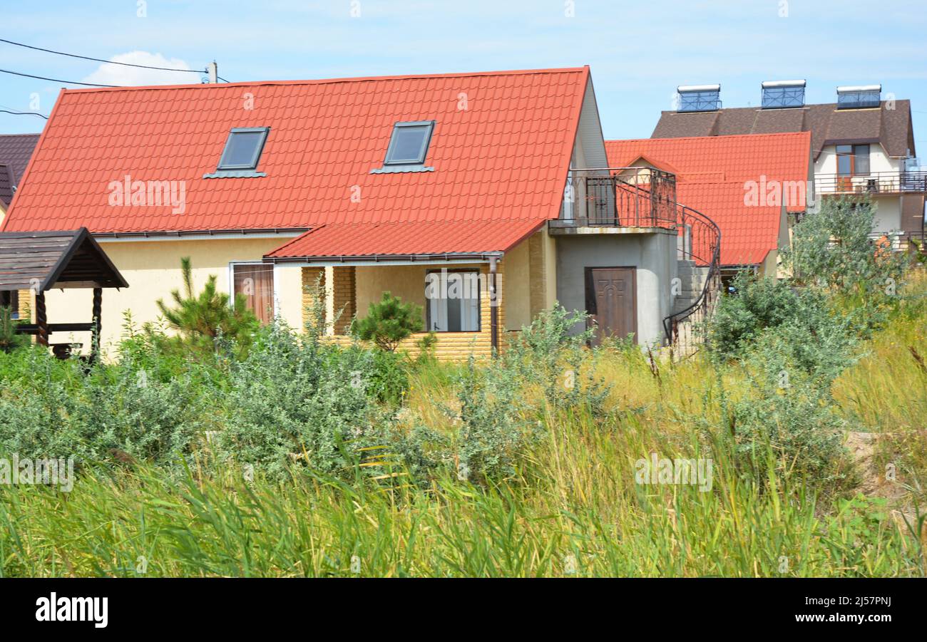 Cozy cottage house with red metal roof, balcony and attic window ...