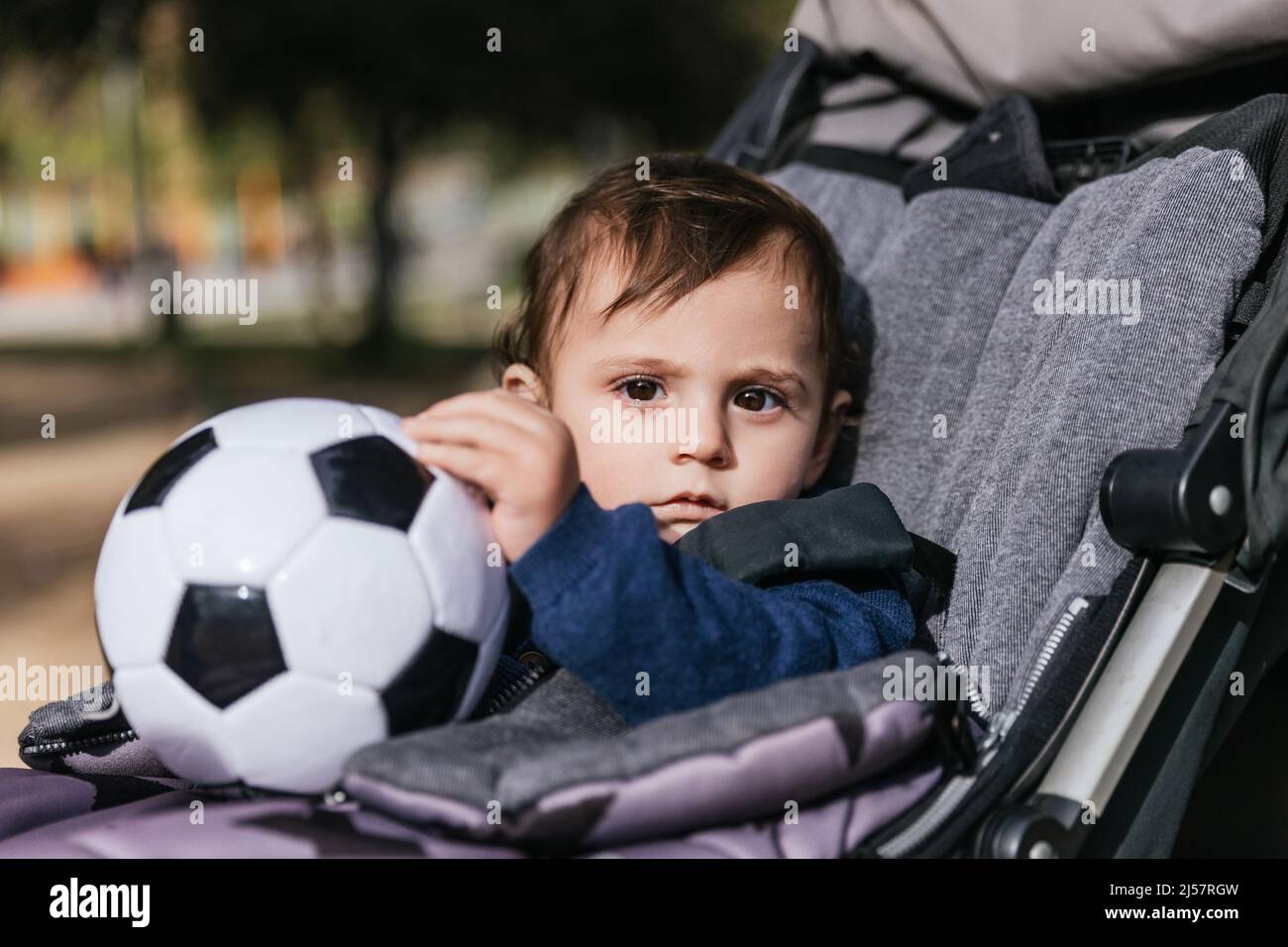 A little boy in his stroller holding a soccer ball in the park Stock ...