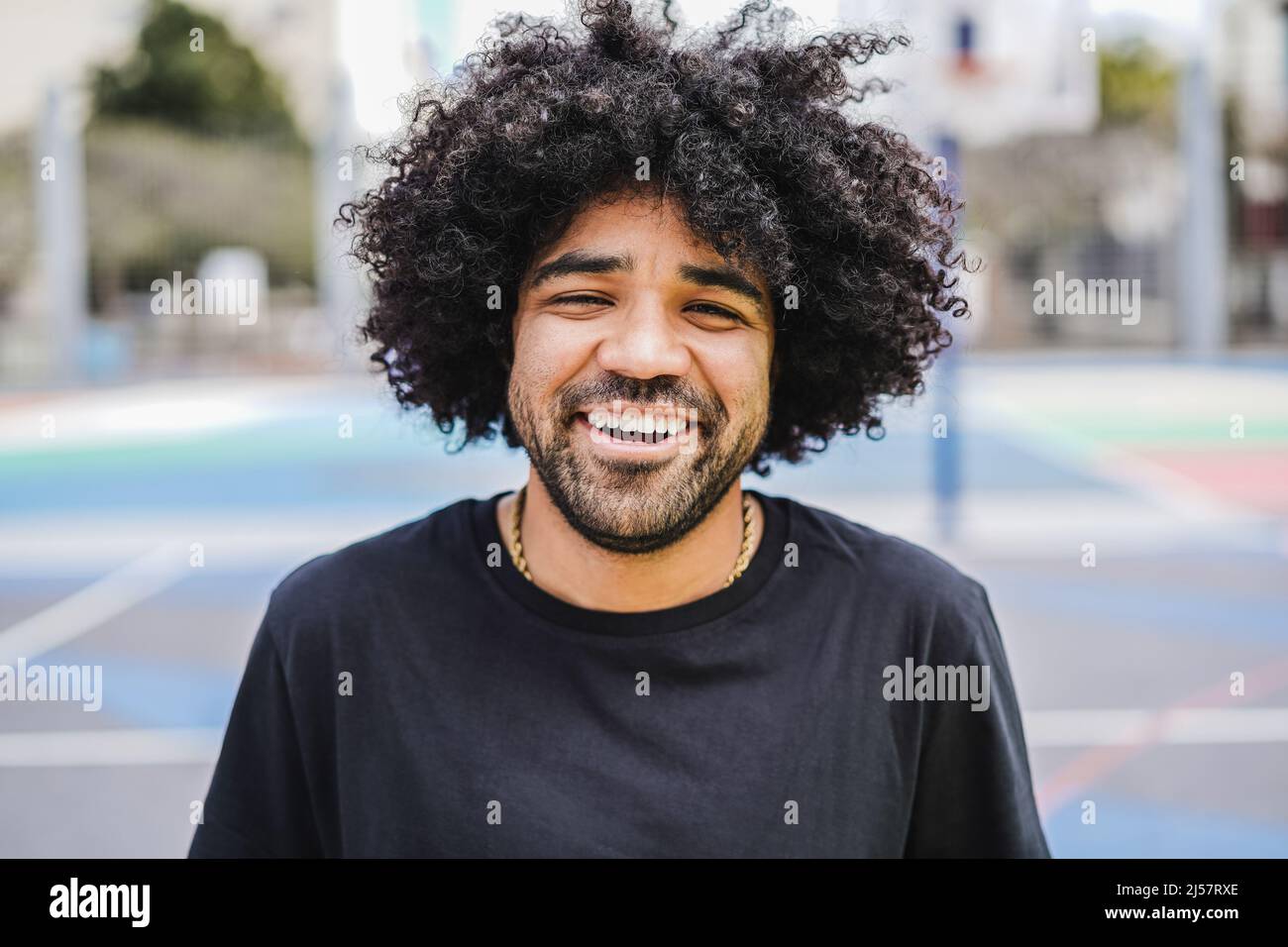 Happy African man smiling at camera inside basketball court - Focus on ...