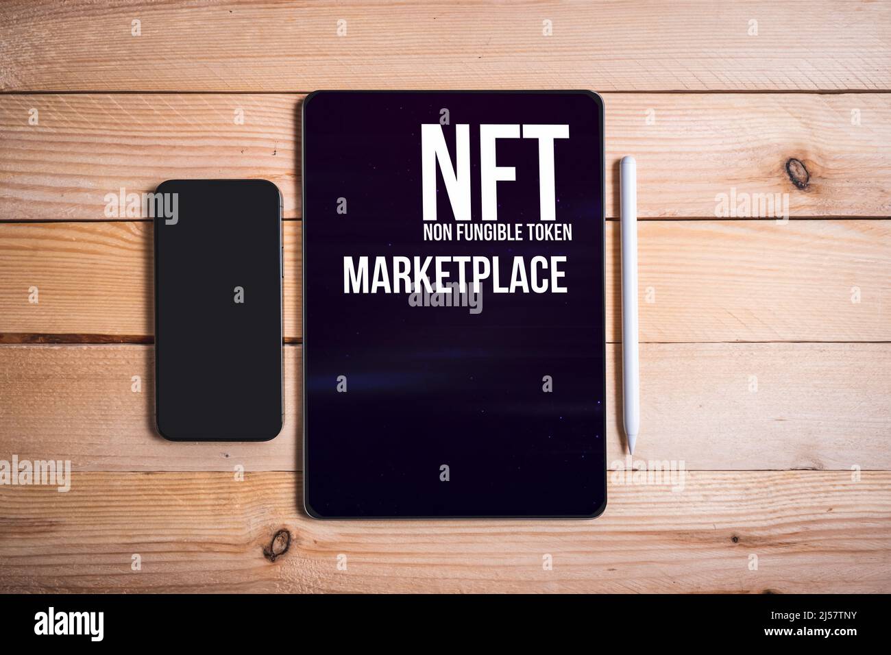 Tablet with pen on wooden table with a wallpaper of an NFT marketplace ...