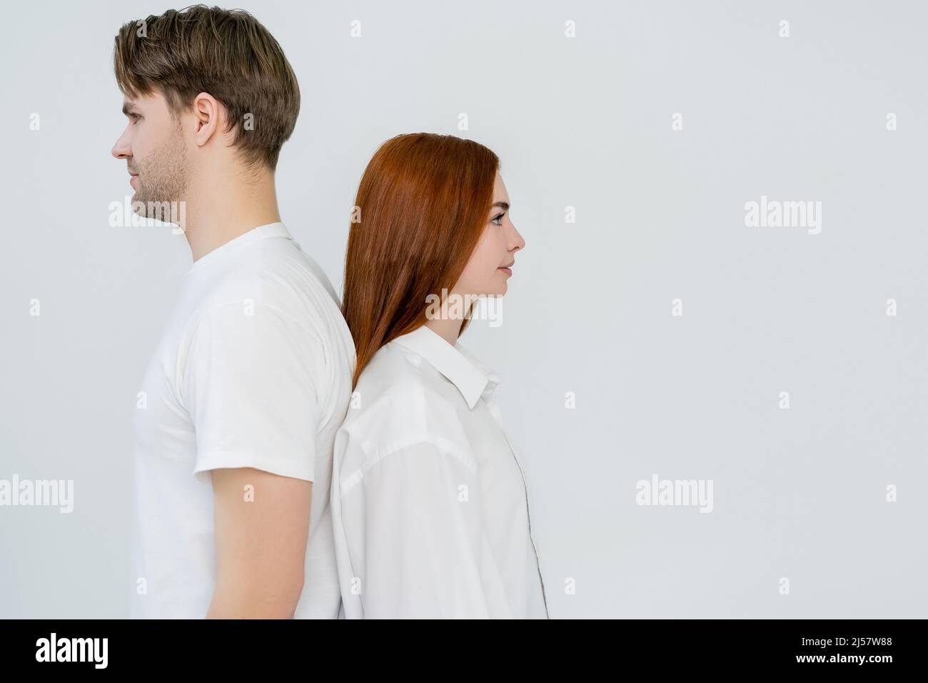 Side view of young couple standing back to back isolated on white Stock ...
