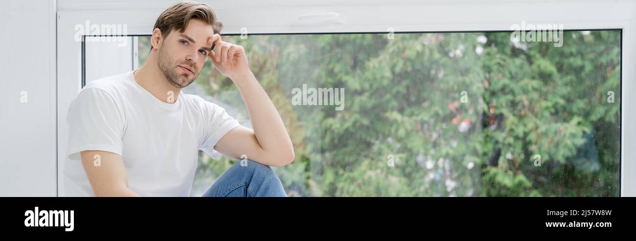 Young man looking at camera near window at home, banner Stock Photo - Alamy