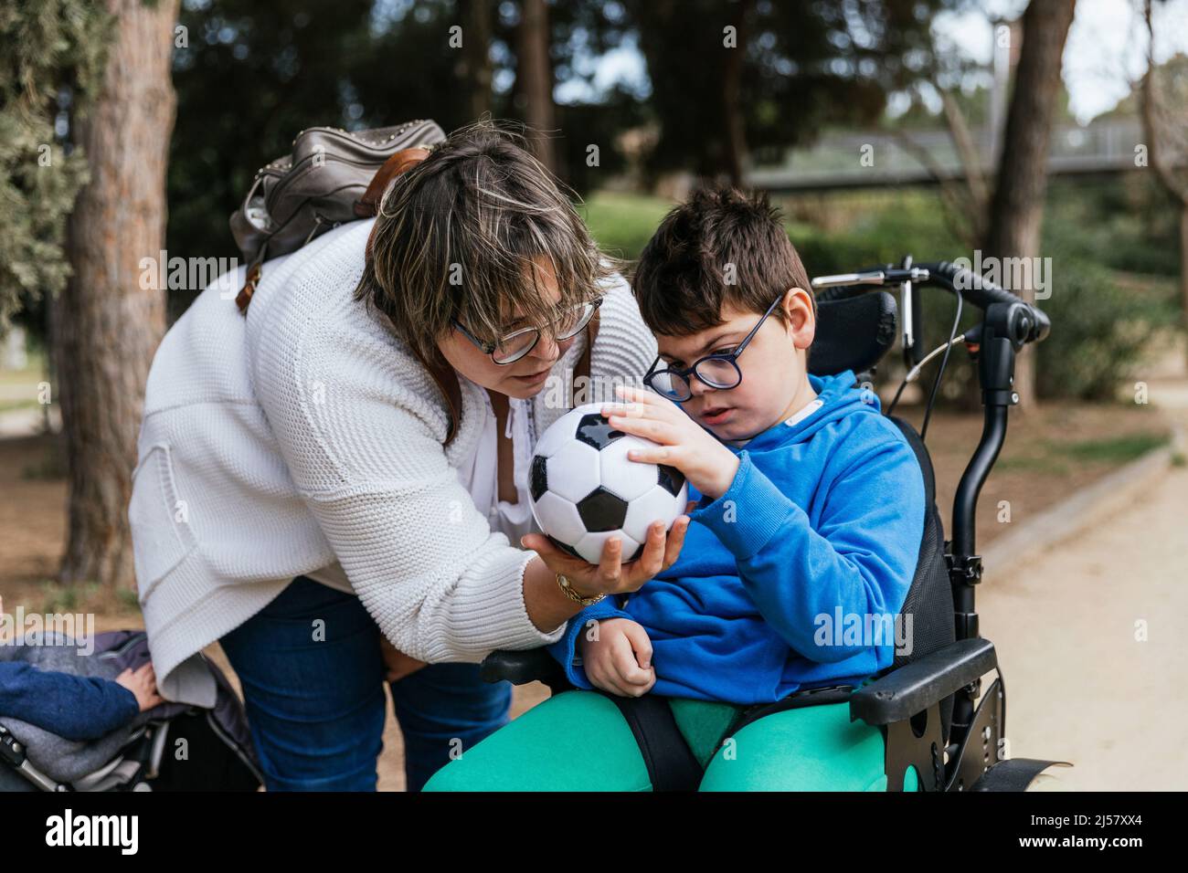 Child with multiple disabilities in a wheelchair playing with a soccer ...