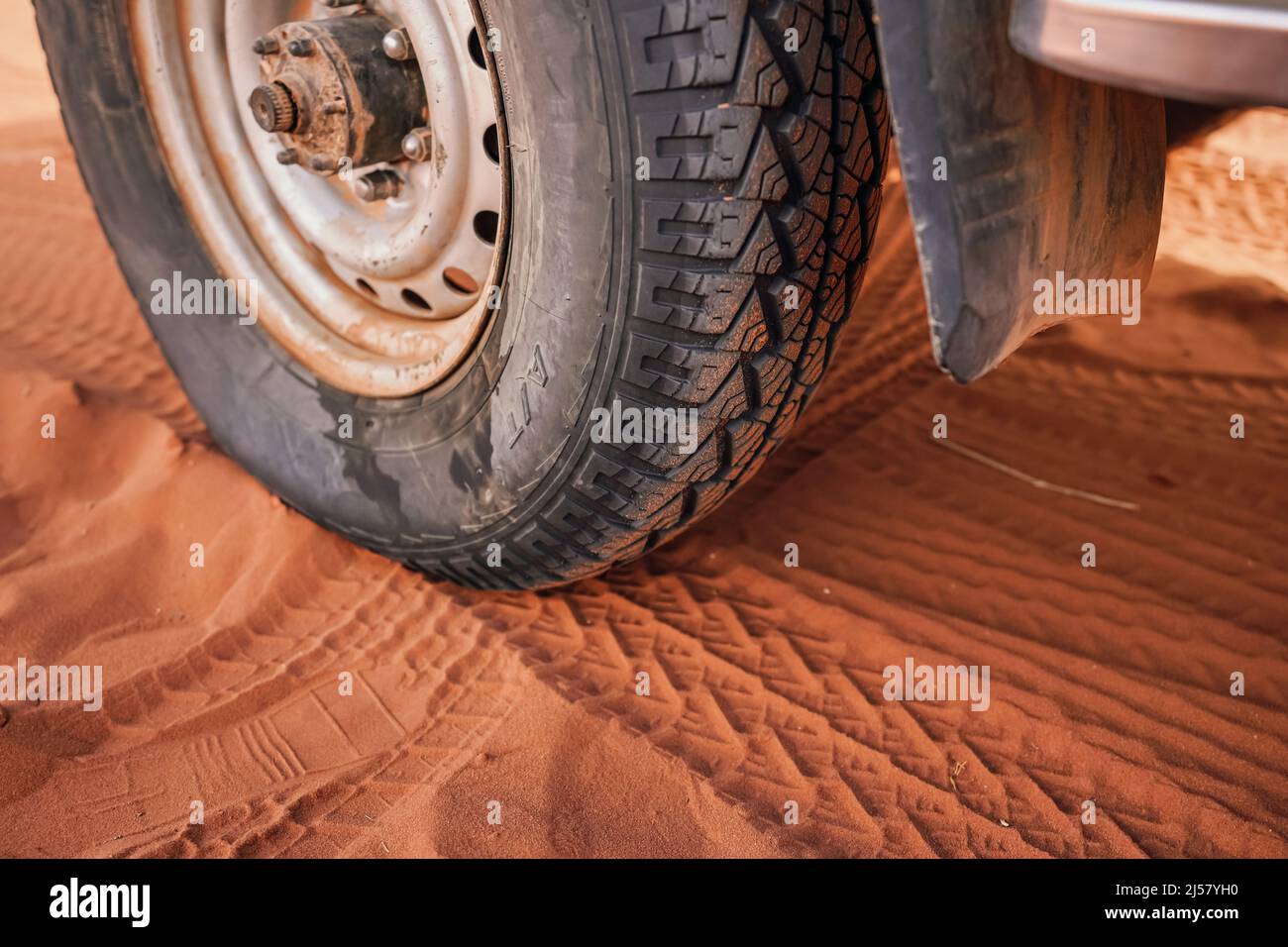 4wd vehicle tyre, dirty from dust - track print visible in red sand ...