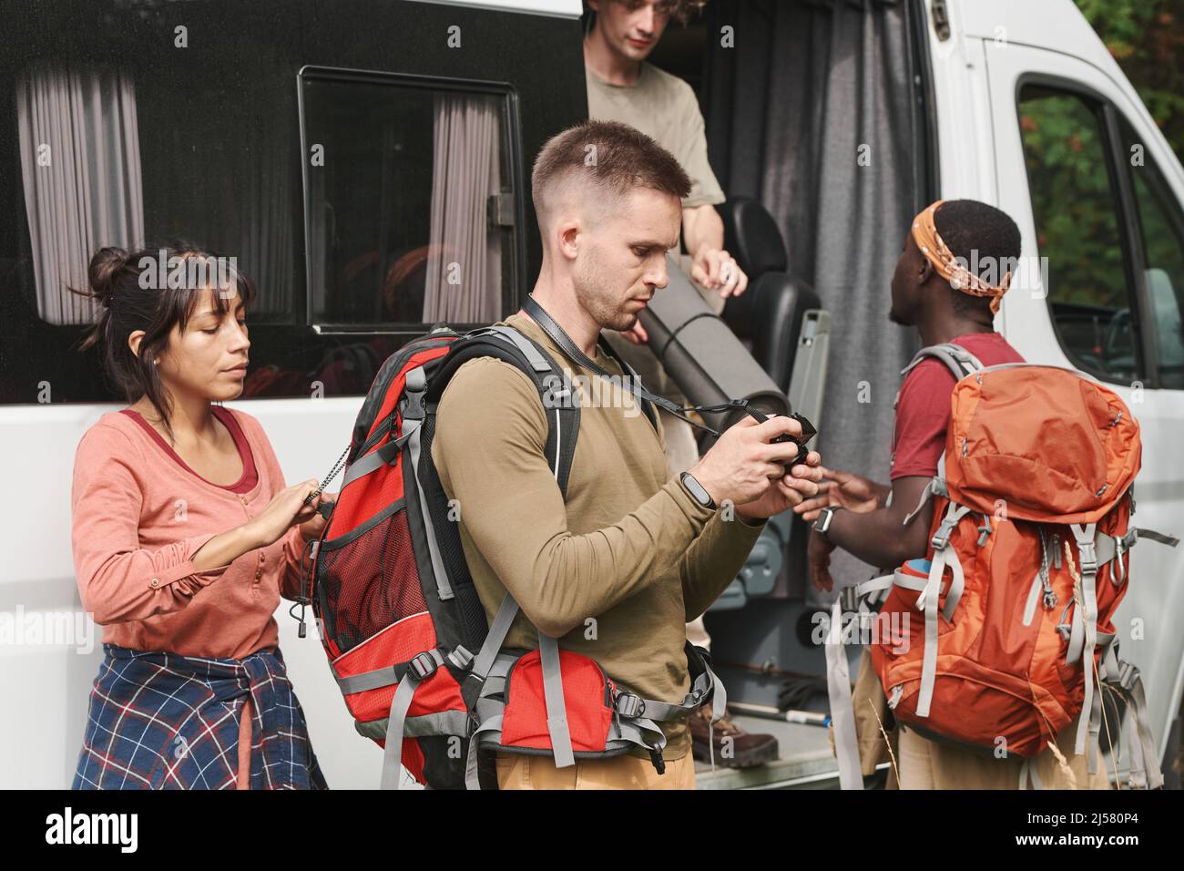 Serious young man looking through photos on camera display while his ...