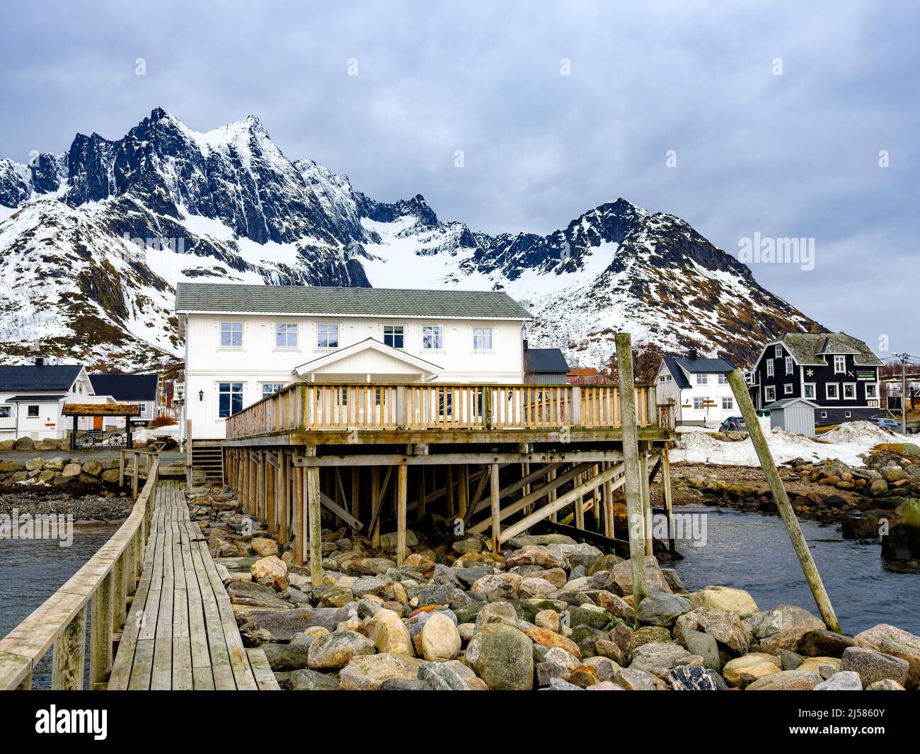 Wooden houses on the coast, rugged peaks behind, Mefjordvaer, Senja ...