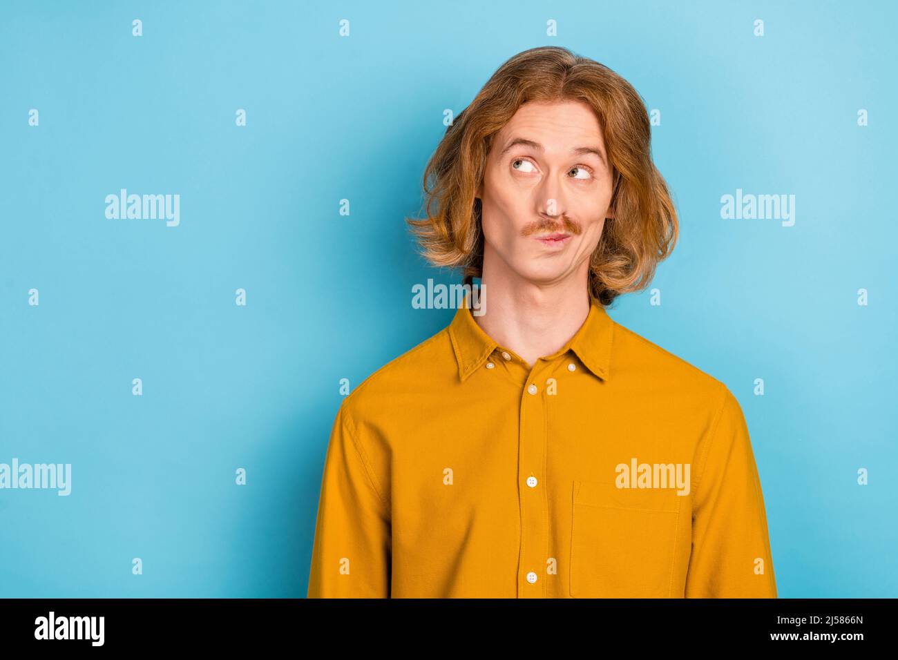 Portrait of attractive bewildered long-haired guy deciding copy space ...