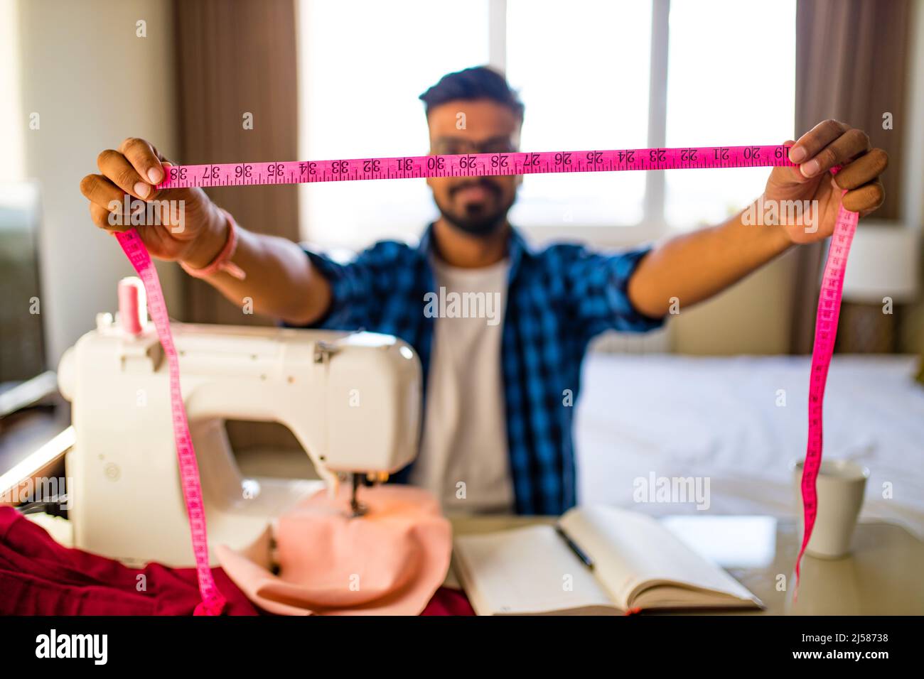 arabian man designer sewing clothes on sewing machine in studio ...