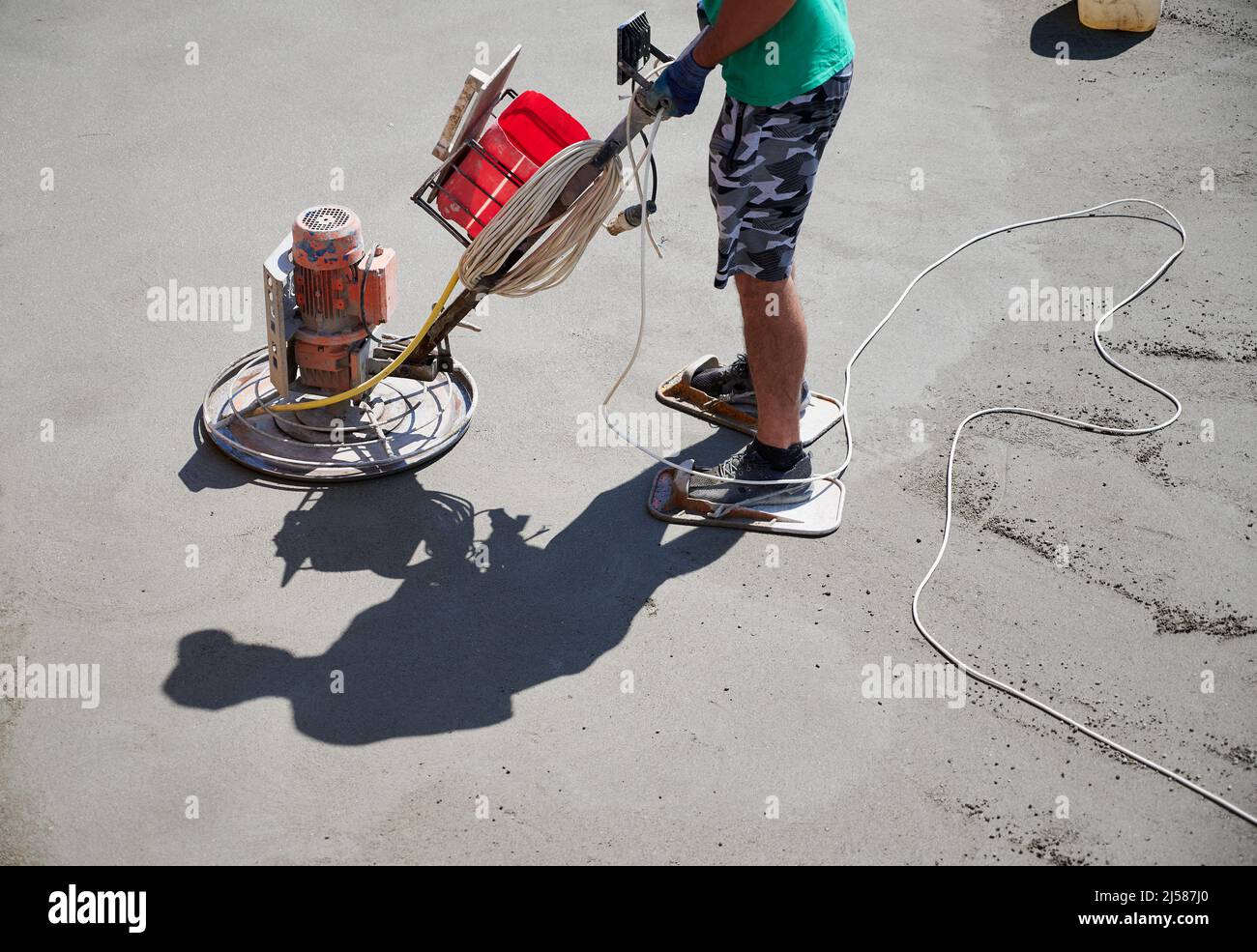Close up of man builder using troweling machine while screeding floor ...