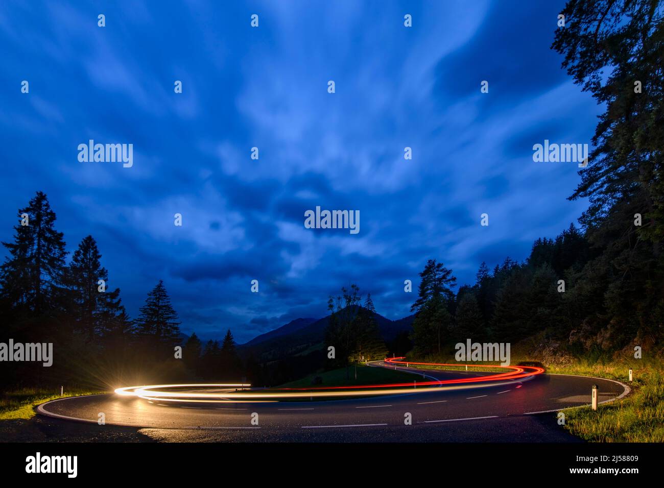 Fahrendes Auto in Serpentiene mit Lichtstreifen bei blauer Stunde ...
