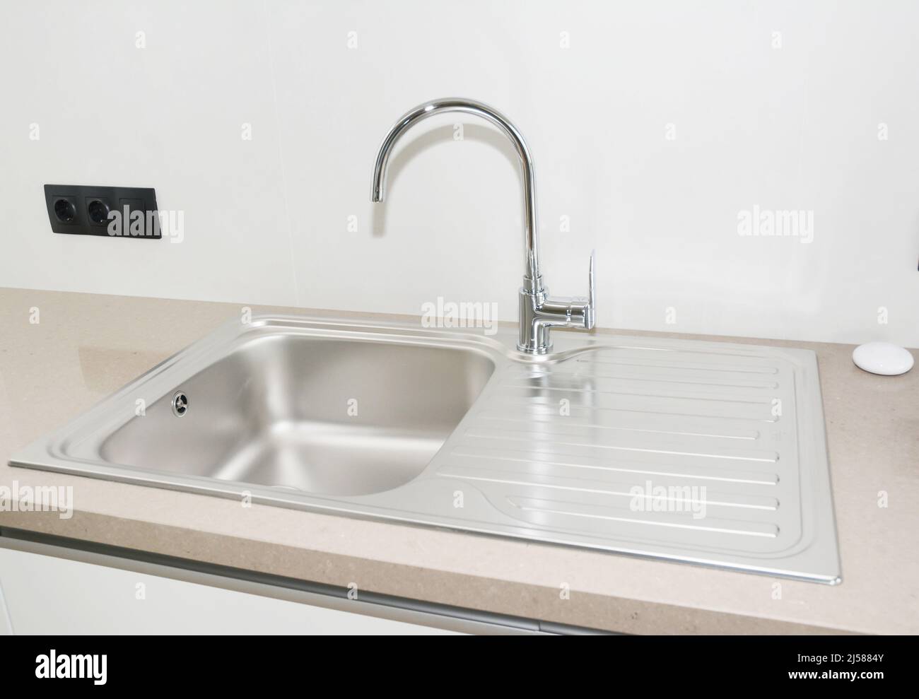 Close up on modern kitchen metal faucet and metal basin kitchen sink ...