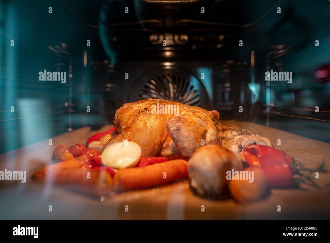 Crispy roasted chicken in a hot oven. Front view through the pane ...