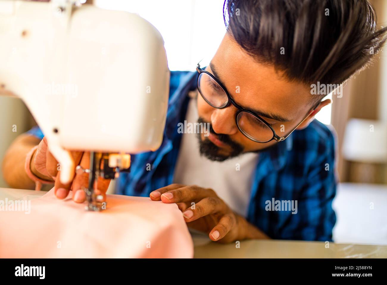 arabian man designer sewing clothes on sewing machine in studio ...