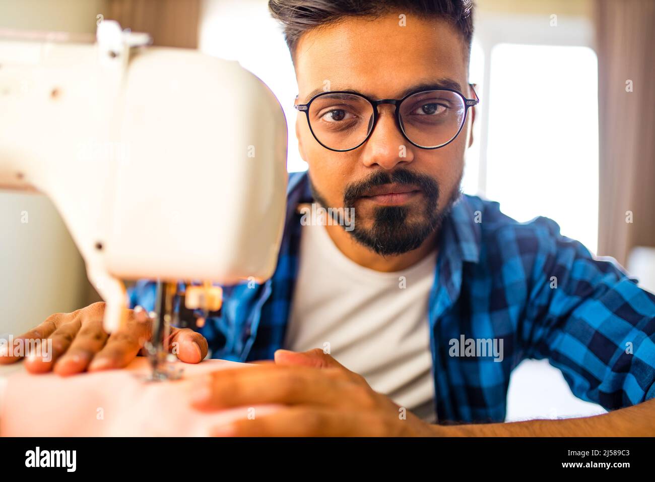 arabian man designer sewing clothes on sewing machine in studio ...