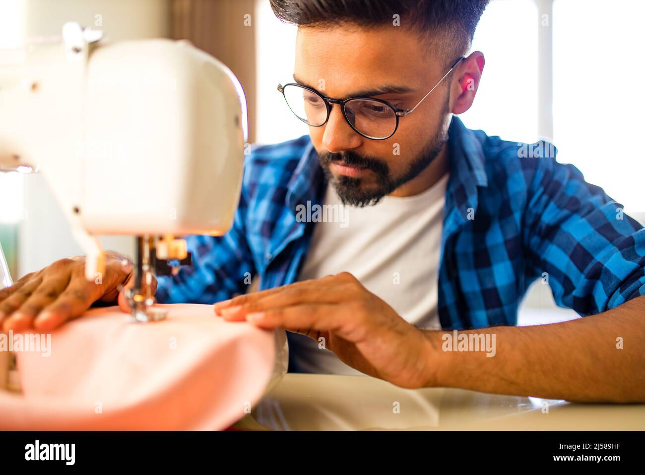arabian man designer sewing clothes on sewing machine in studio ...