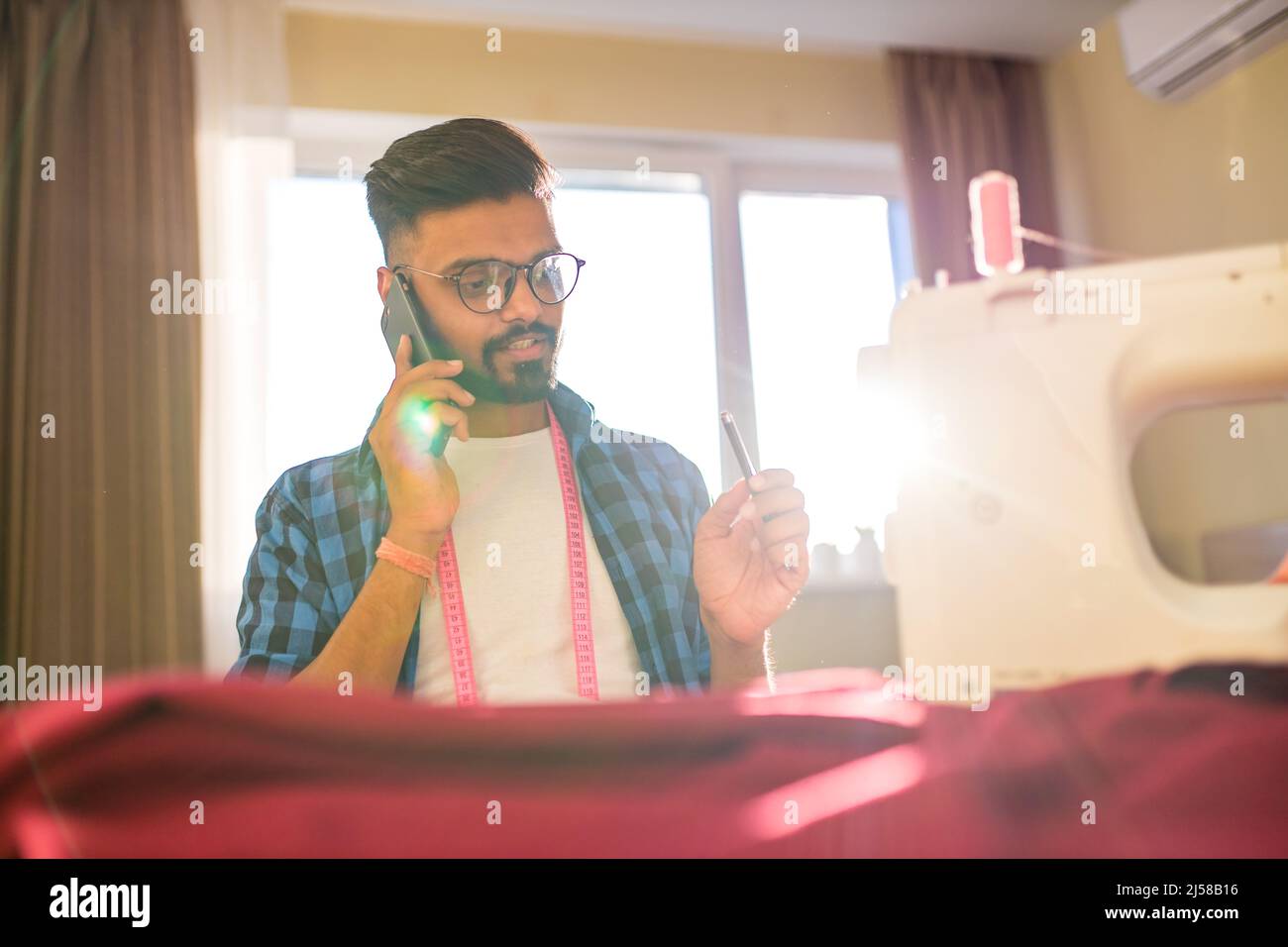 arabian man designer sewing clothes on sewing machine in studio ...