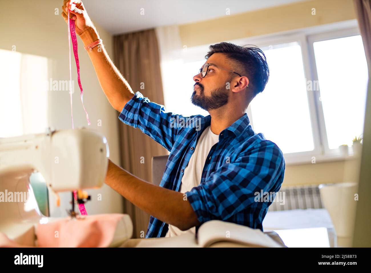 arabian man designer sewing clothes on sewing machine in studio ...