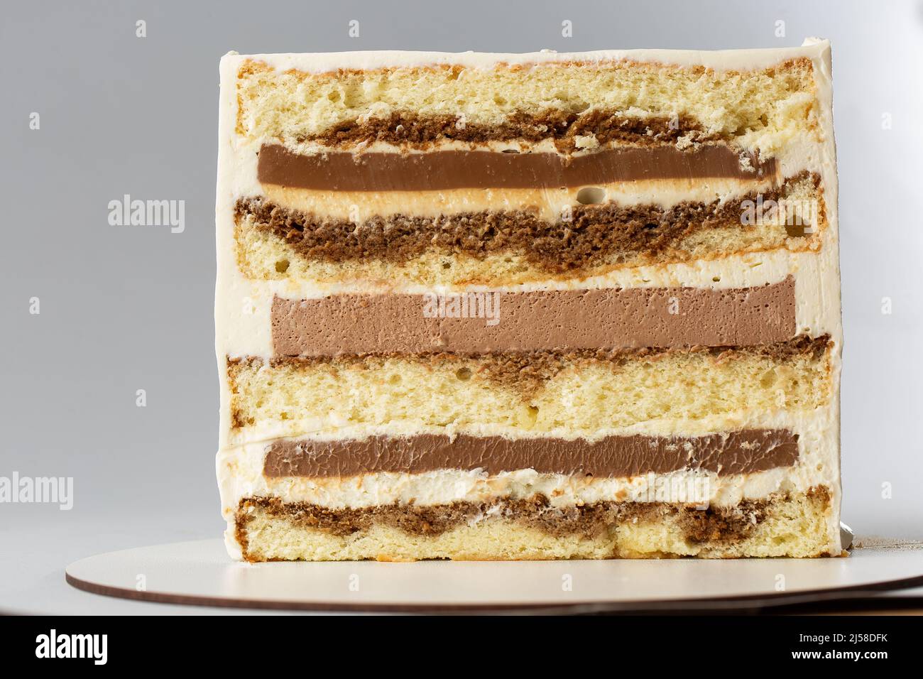 On a white background, a sweet pastry cake is cut in half, the cake is ...