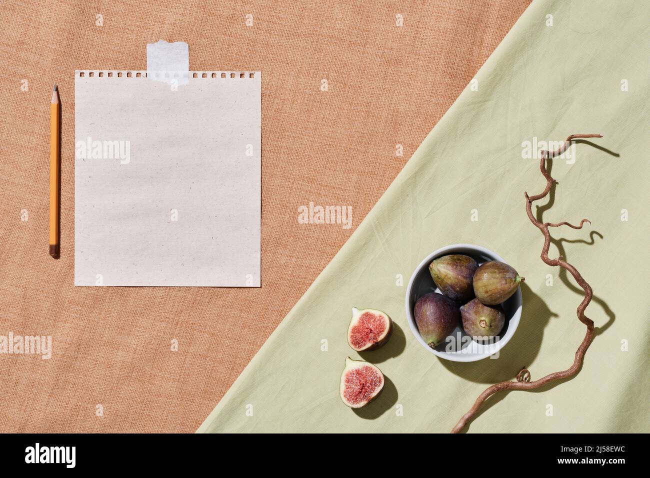Above view of juicy figs in bowl and pieces near it and blank notepad ...
