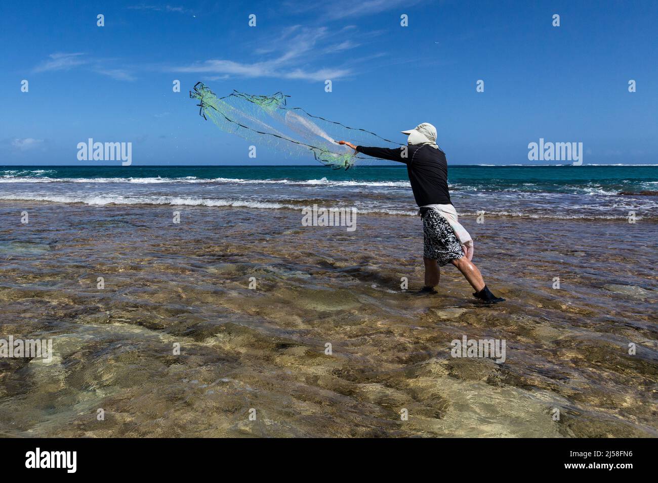 A fisherman casts his net in the surf on Haena Beach on the Island of ...