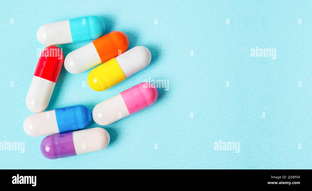 Colorful capsules (pills) on a blue background. Medical background ...