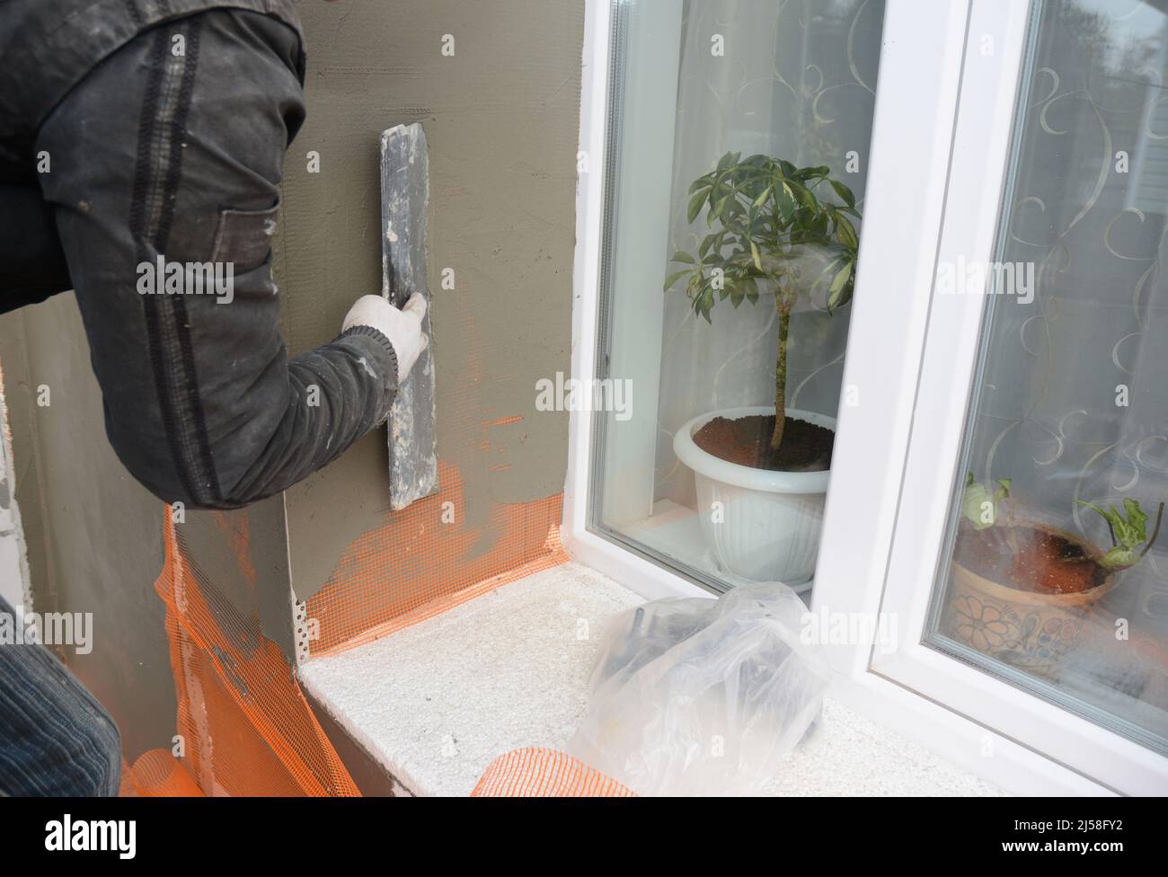 Building contractor plastering wall with fiberglass mesh, stucco ...