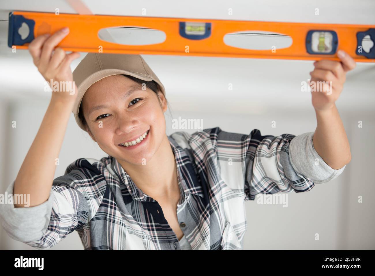 woman using a spirit level on a ceiling Stock Photo - Alamy