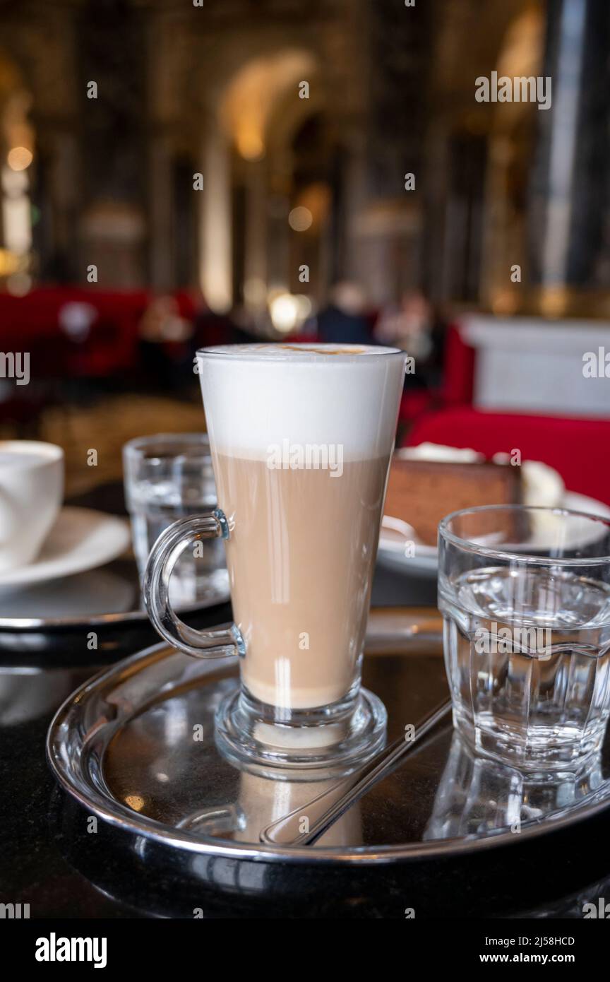 Glass cup of coffee latte served in classic old Austrian café ...