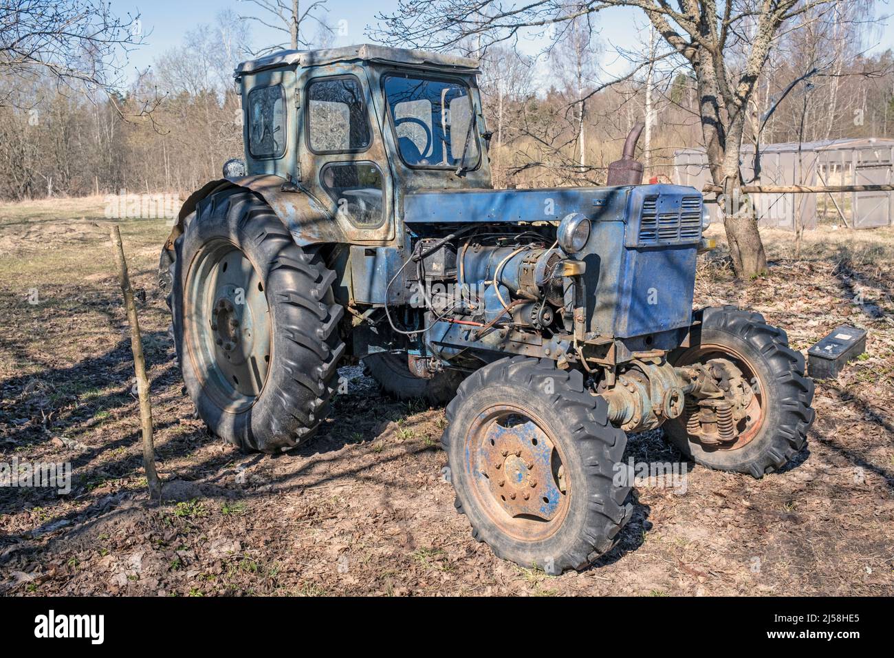 Old rusty Russian tractor in a yard, agricultural mashinery in the ...