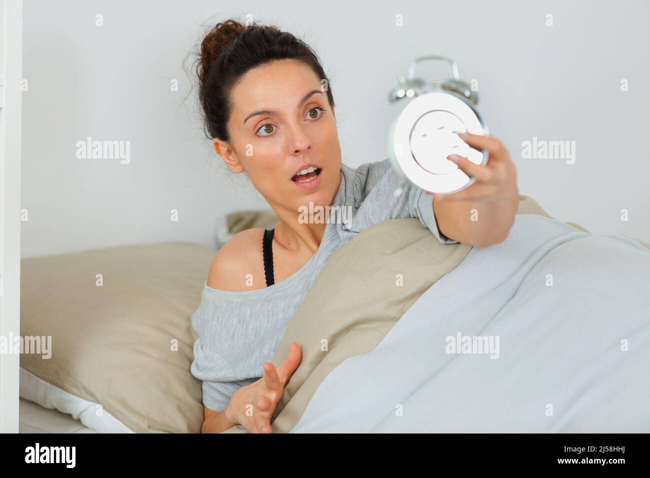 shocked young woman waking up with alarm Stock Photo - Alamy