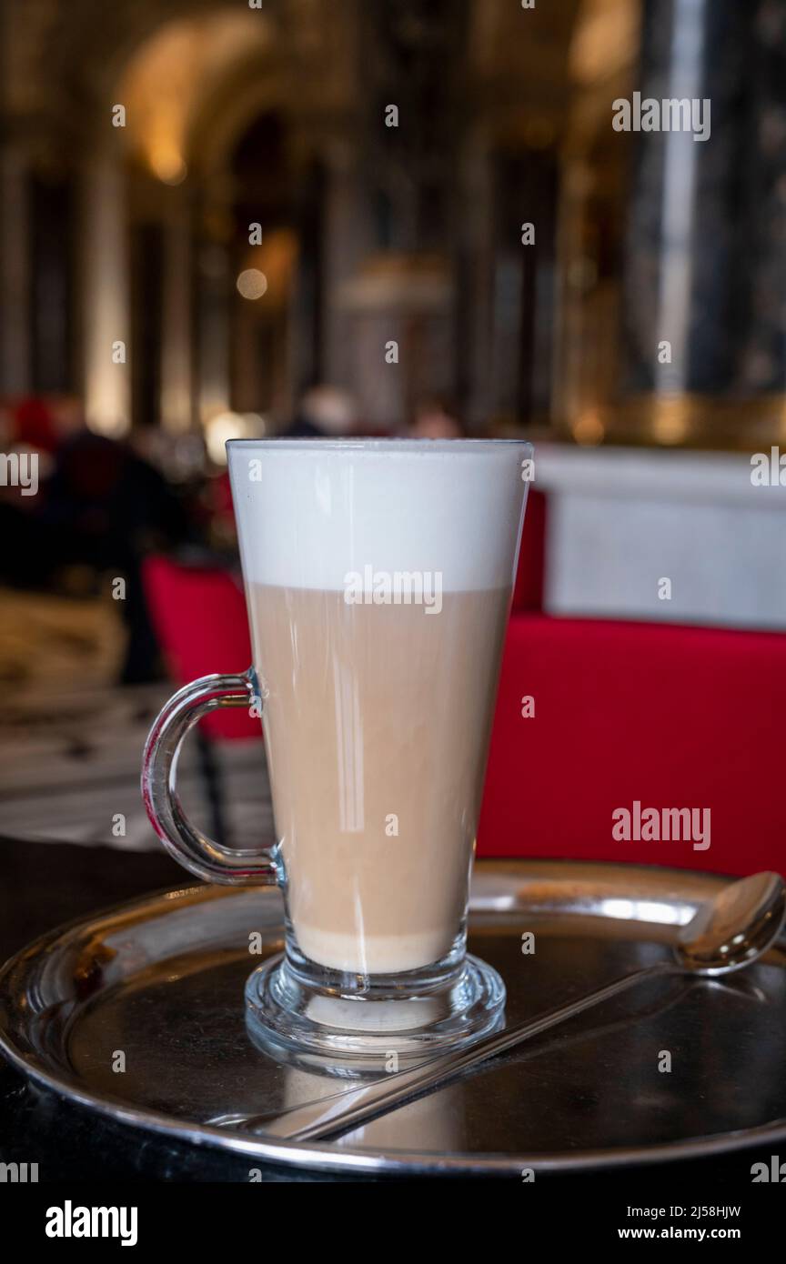 Glass cup of coffee latte served in classic old Austrian café ...