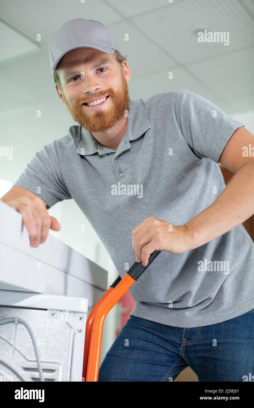 male professional mover in uniform placing the modern washing machine ...