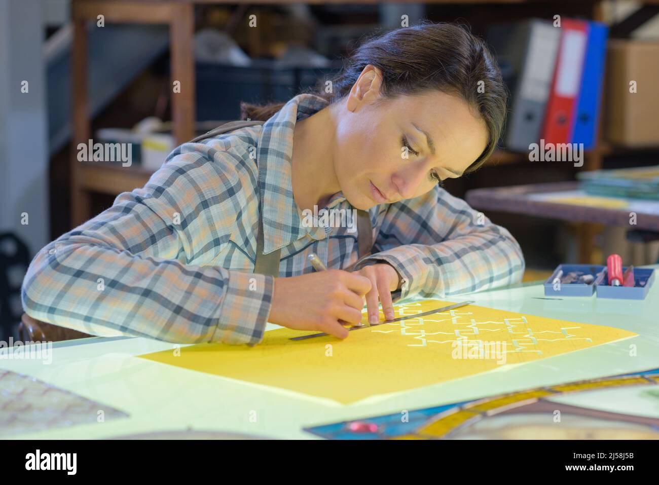 artist cutting out pattern working on illuminated light box surface ...
