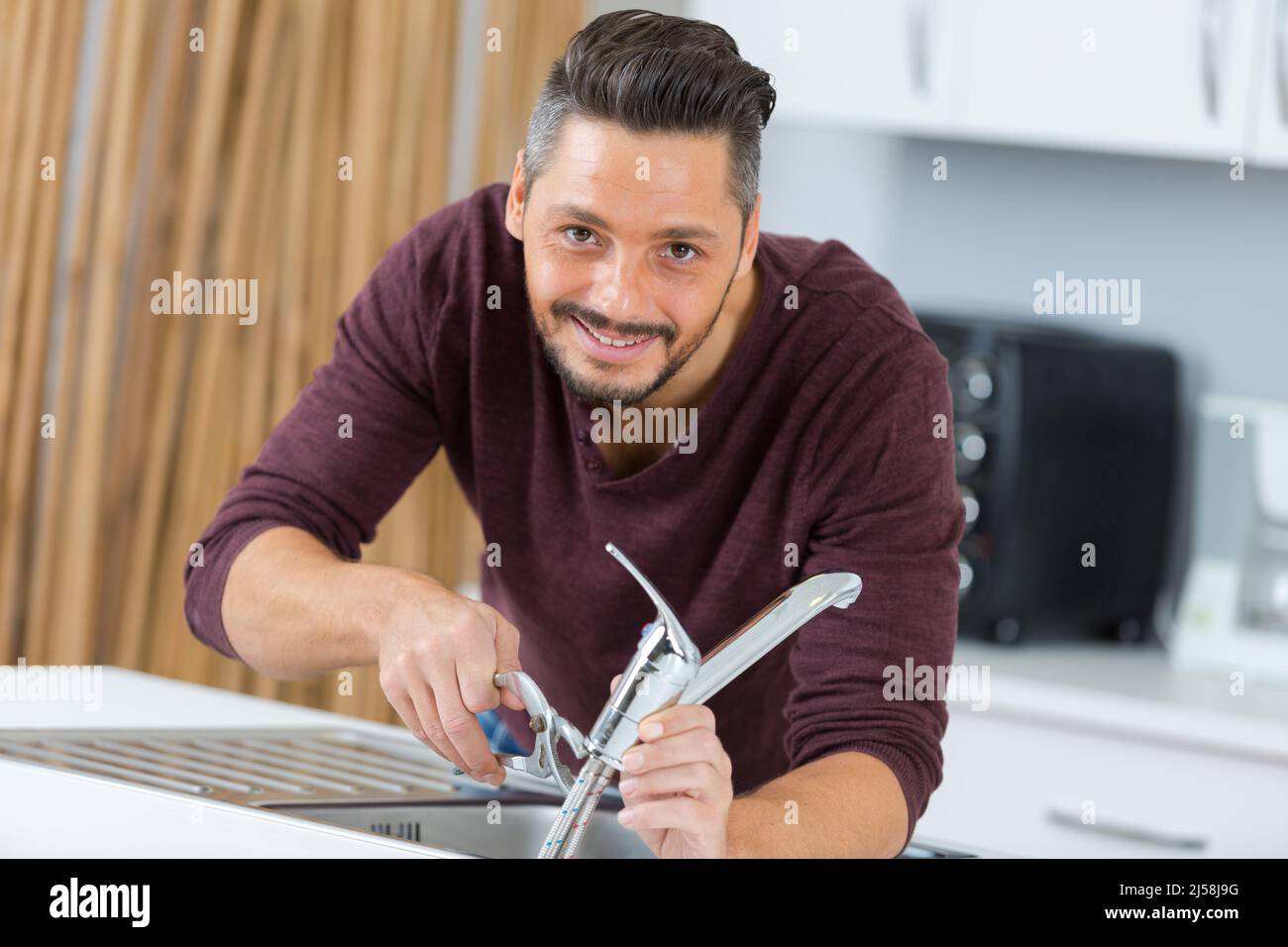 happy man fixing tap in the kitchen at home Stock Photo - Alamy