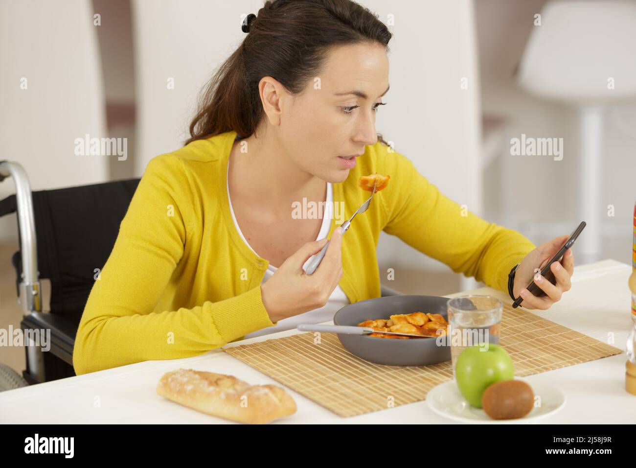disabled woman eating meal and looking at her telephone Stock Photo - Alamy