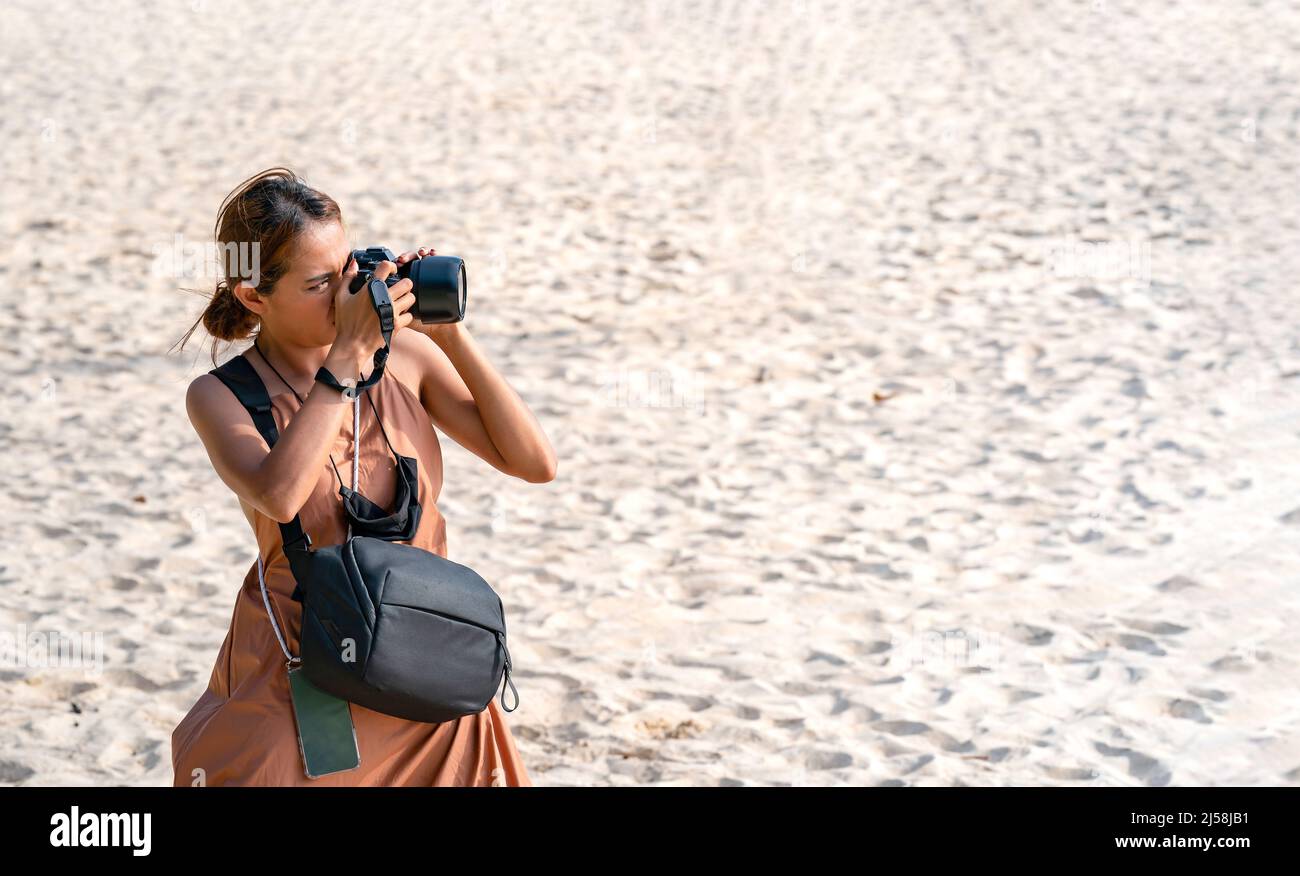 Smart Asian Woman takes a photo with her Digital Camera on the beach in ...