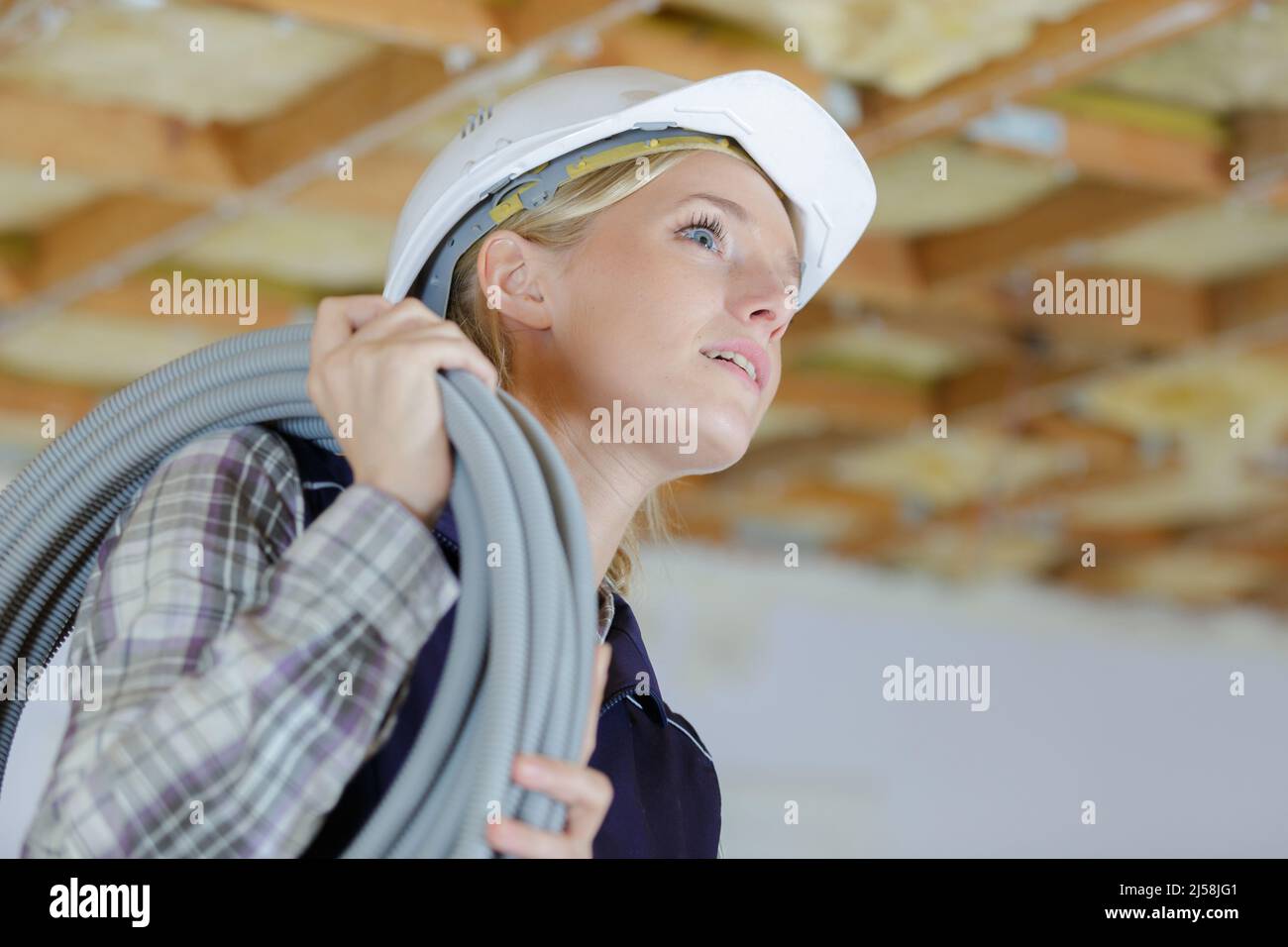female builder carrying cable on her shoulder Stock Photo - Alamy