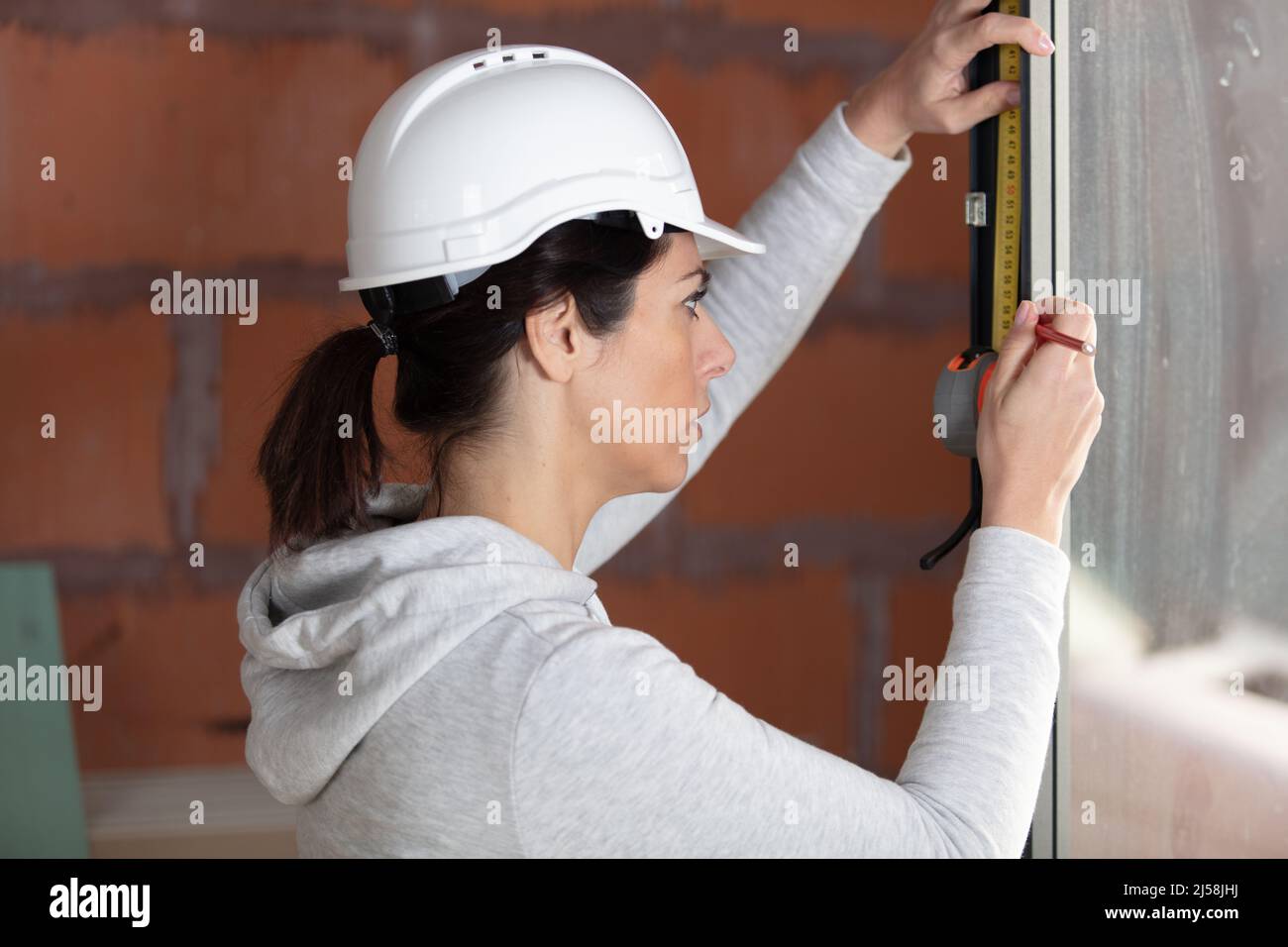 female builder using spirit level on newbuild window Stock Photo - Alamy