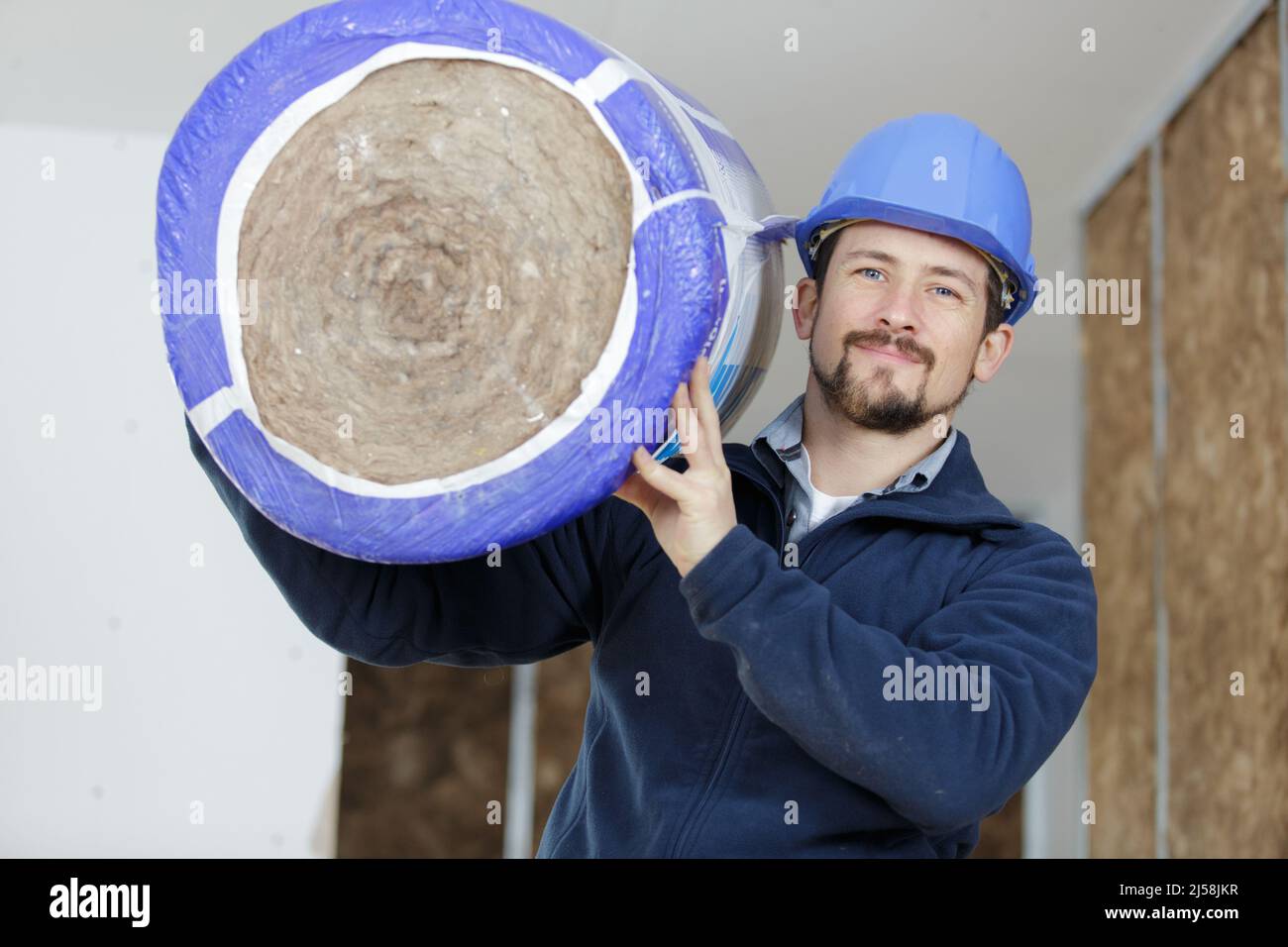 workman carrying a roll of insulation Stock Photo - Alamy