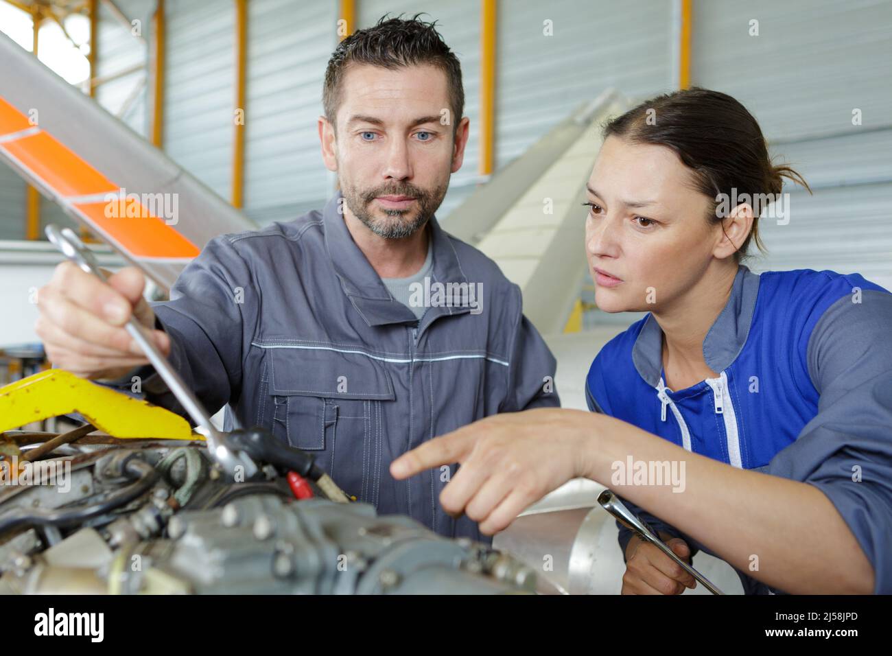 couple of workers reapiring together industrial engine Stock Photo - Alamy